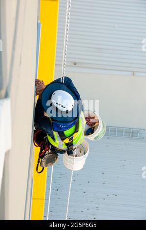 Rope access technician suspended by safety ropes carrying out ...
