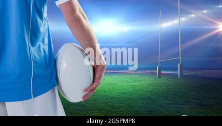 Composition of male rugby player holding rugby ball over sports stadium ...