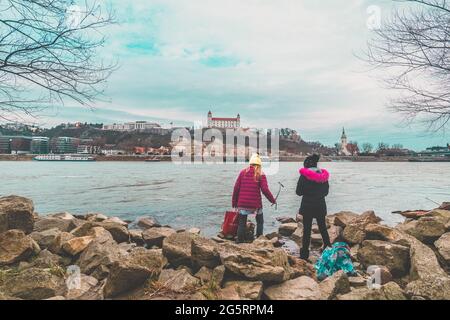 two children playing by the river Danube with views to the Bratislava ...