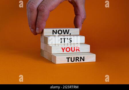 Now, it's your turn symbol. Wooden blocks form the words 'now, it's ...
