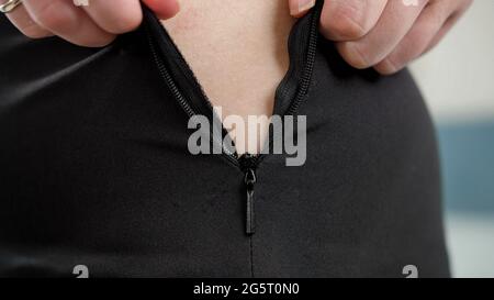 CLoseup of woman pulling stuck zipper on small tight dress. Concept of ...