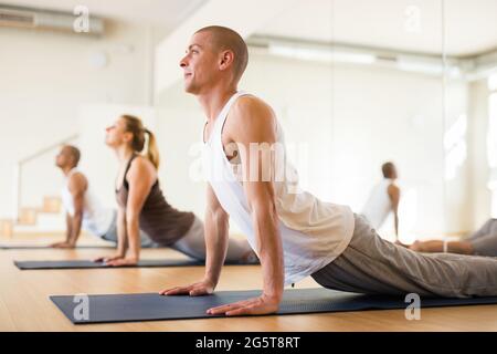 Nice people exercising during yoga class in fitness center Stock Photo ...