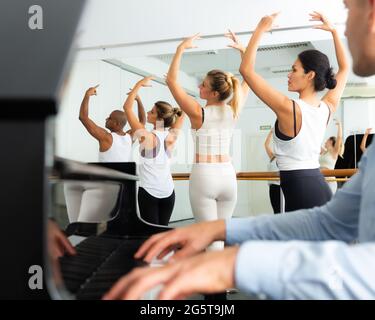 Diverse group of women practicing ballet exercises at a barre in a ...
