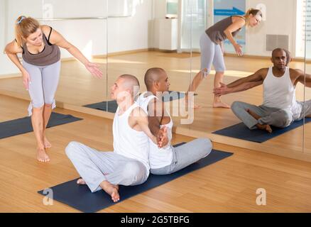 Yoga teacher helps couples learn yoga poses Stock Photo - Alamy