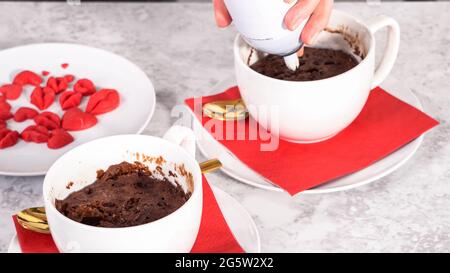 Chocolate mug cakes garnished with whipped cream and chocolate hearts ...