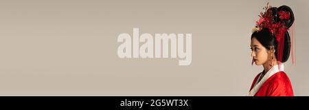 Asian woman with decor in hairdo holding sword isolated on grey Stock ...