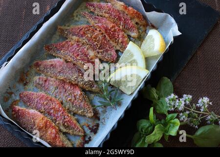 Baked gurnard fillet with lemon and herb on a tray. Directly above ...