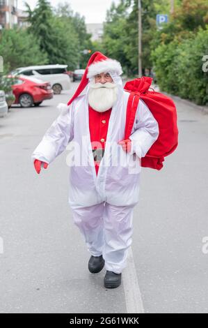 Santa claus walking at a pedestrian crossing and carrying a surfboard ...