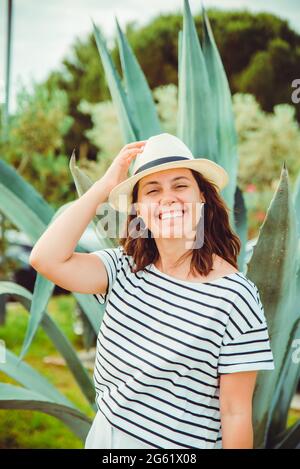 smiling pretty woman in fedora hat sitting in outdoors restaurant ...