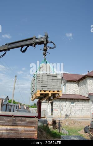 Unloading paving slabs from a truck. Men unload paving slabs using a ...