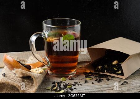 A glass mug of fragrant brewed flower tea on a wooden table, with tea ...