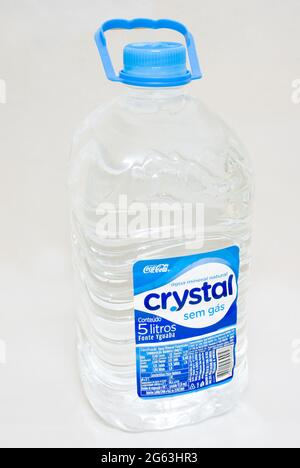 A five-liter plastic water bottle lies on a black wooden board, bottled ...