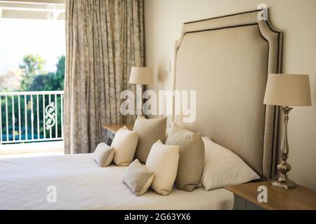 General view of luxury sunny bedroom with large bed and night tables ...