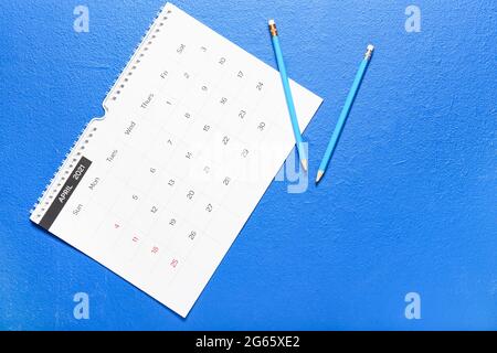 Flip paper calendar and pencils on color background Stock Photo - Alamy