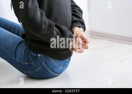 Female hostage with tied hands sitting on chair in room Stock Photo - Alamy