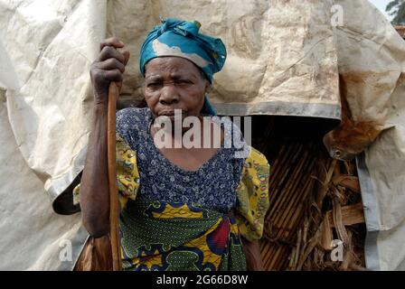 A Congolese displaced woman stands in front of a makeshift straw hut ...