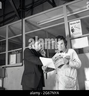 1970s, historical, inside a car repair workshop, two garage mechanics ...