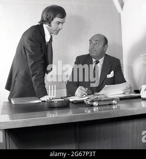 1970s, historical, suited business executive sitting at his desk using ...