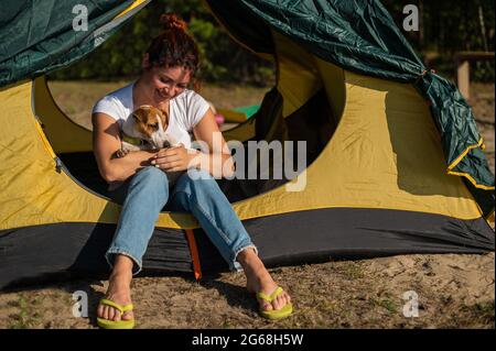 Red-haired Caucasian woman hugs a dog and lives in a motor home. Travel ...