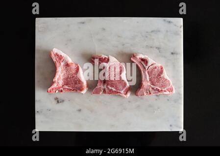 Raw Iberian pork chops on a white marble table Stock Photo - Alamy