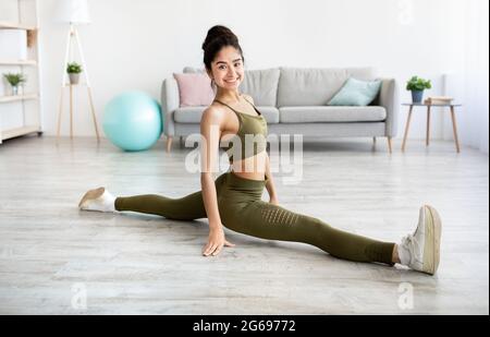 Sporty Indian woman sitting in splits, doing legs stretch, improving ...