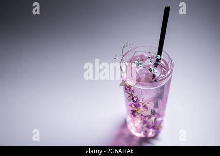 luxury violet fizz cocktail drink with flower decoration on grey ...