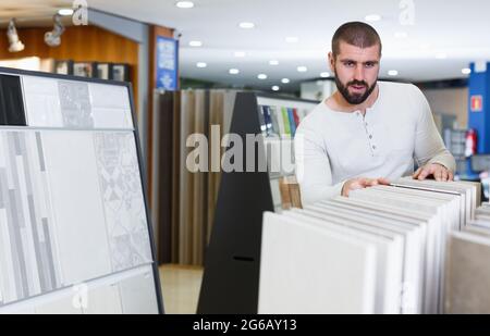 Portrait of man customer choosing ceramic tile in domestic shop Stock ...