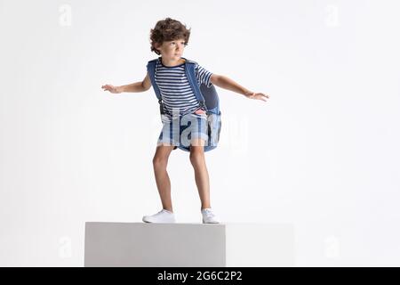 Caucasian preschool boy standing on big box isolated over white studio ...