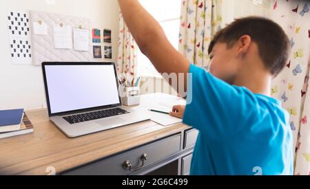 Caucasian boy raising hand for video call, with smiling diverse ...