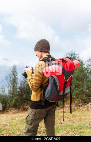 Side view of female backpacker taking picture of mountainous landscape ...