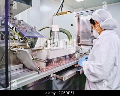 Woman worker in uniform operating machine at factory concentrate on ...