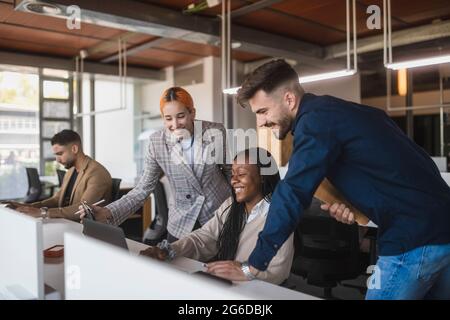 Group of cheerful multiracial coworkers discussing project during work ...