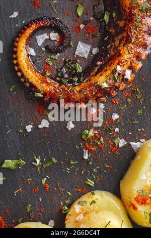 Top view of fried octopus tentacle and pieces of potato served with ...