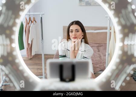 blurred phone holder with ring lamp near fashion blogger holding tag ...