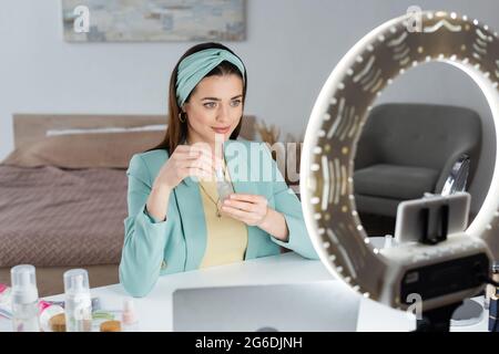 Ring lamp and smartphone near blurred interracial bloggers with ripe ...