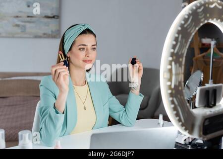 blurred phone holder with ring lamp near fashion blogger holding tag ...