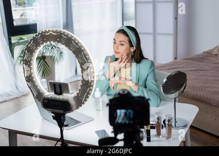 beauty blogger applying face foam on hand near gadgets and ring lamp ...