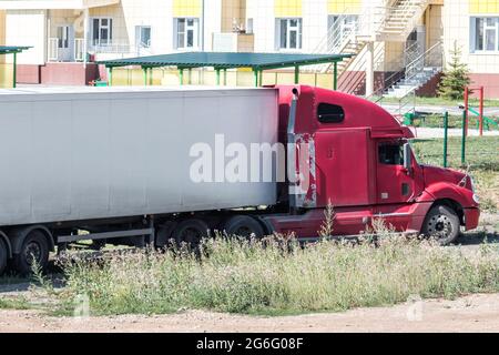 Red long-distance bonnet truck with a white semitrailer on bright ...