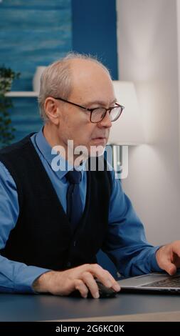 Focused grey man drinking coffee while working with computer in office ...