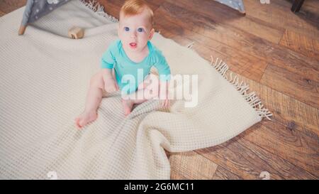 high angle view of cute infant girl in baby romper sitting near teddy ...