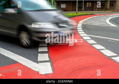 Red cycle lane marking in an inner-city roundabout, to make drivers ...