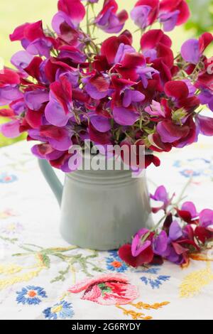 Summer arrangement of sweet pea flowers in a vase on a garden table ...
