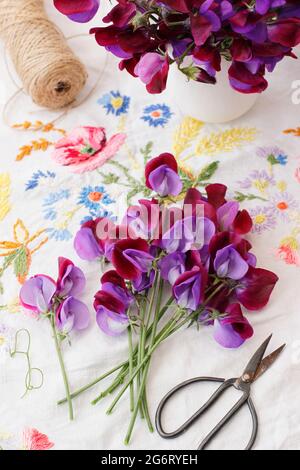 Bunch of sweet peas arranged in a simple white vase jug on a garden ...
