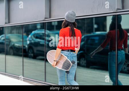 Unrecognized skater girl wearing hat walking in the street and holding ...