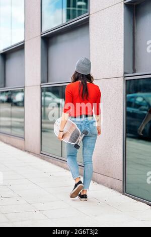 Unrecognized skater girl wearing hat walking in the street and holding ...