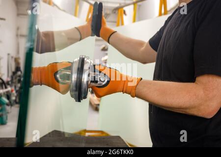 Glazier holding a thick pane of glass with a suction cup, Glass Factory ...