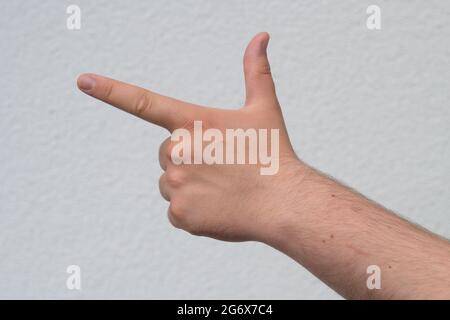 Man giving a finger gun gesture over a white background in greeting or ...