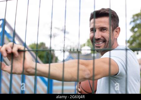portrait of exhausted male basketball player leaning on fence Stock ...