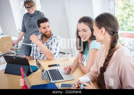 Freelance and remote workers. Smiling young woman pouring coffee in a ...