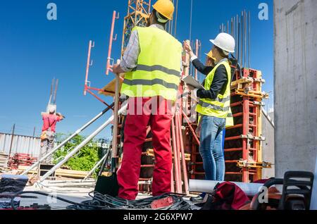 Young female builder and experienced foreman in hardhats and workwear ...